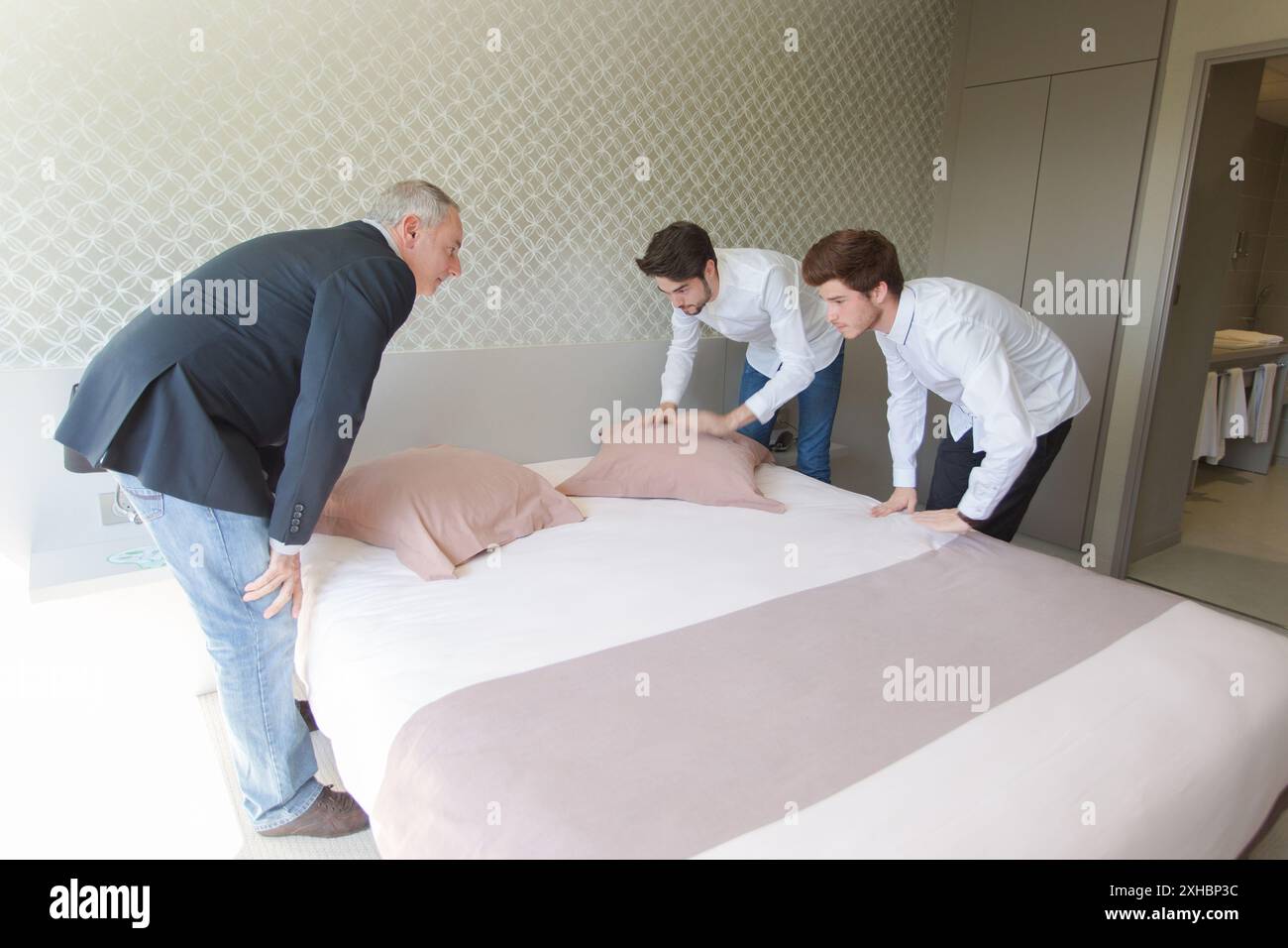 manager training male hotel staff to make a bed Stock Photo - Alamy