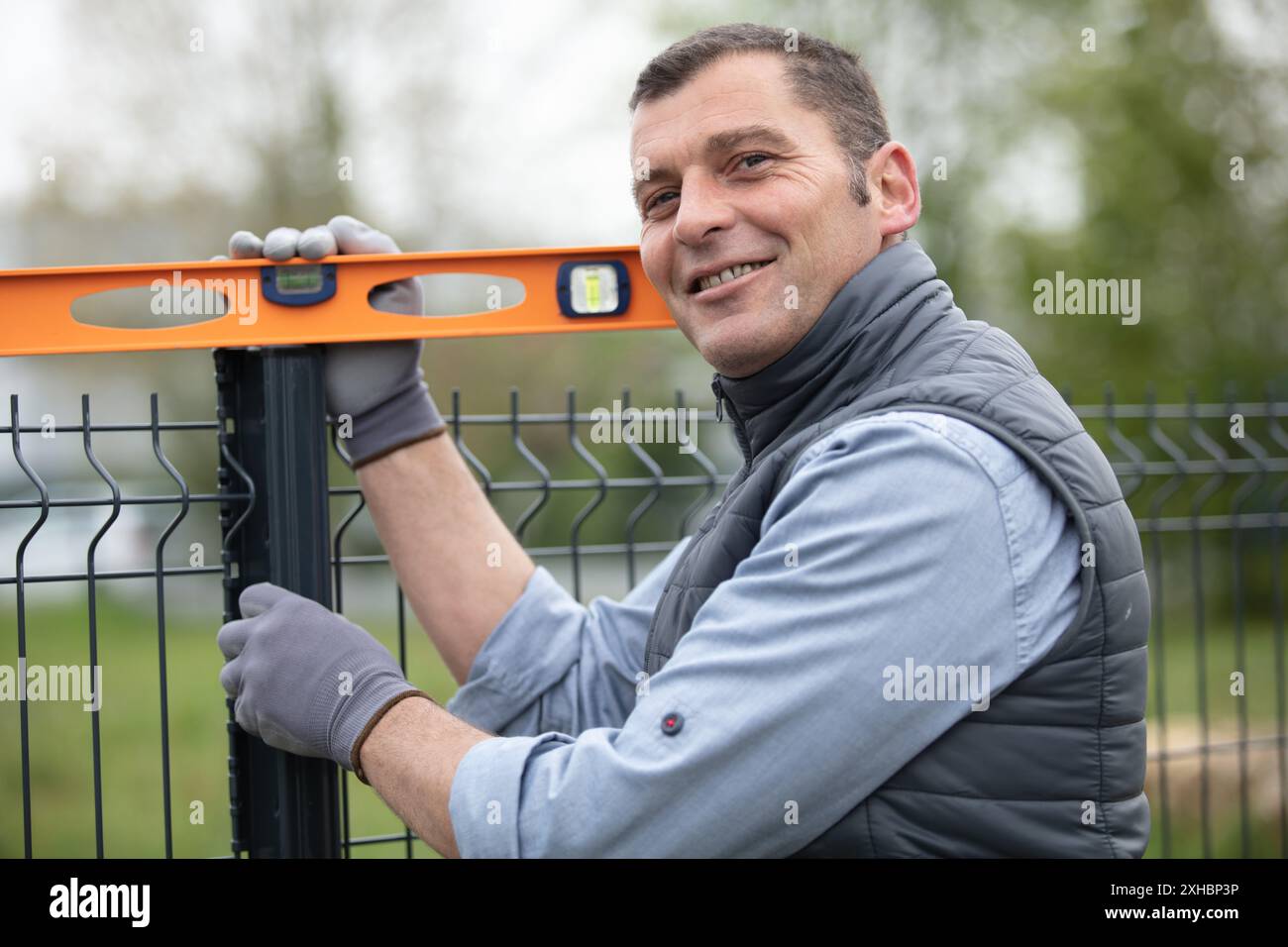 man building metal fence checking with spirit level Stock Photo - Alamy