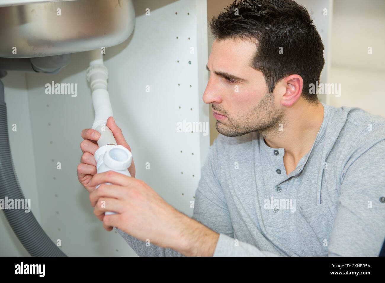 man fitting plumbing fixture under the sink Stock Photo - Alamy