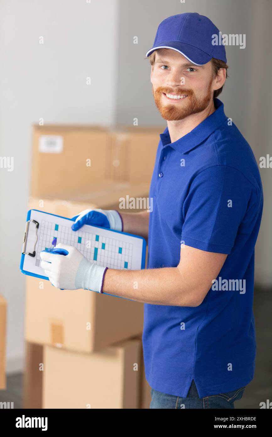 delivery man checking list on clipboard indoors Stock Photo - Alamy