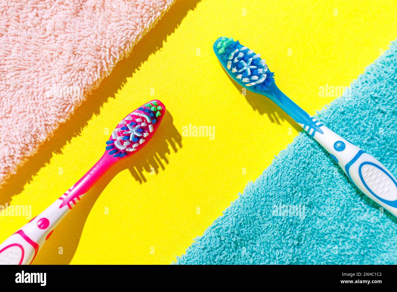 Two vibrant toothbrushes crossed on a yellow backdrop, each on a ...
