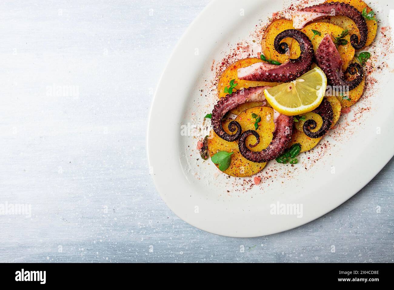 Octopus with potatoes and spices, on a light plate, top view, no people ...