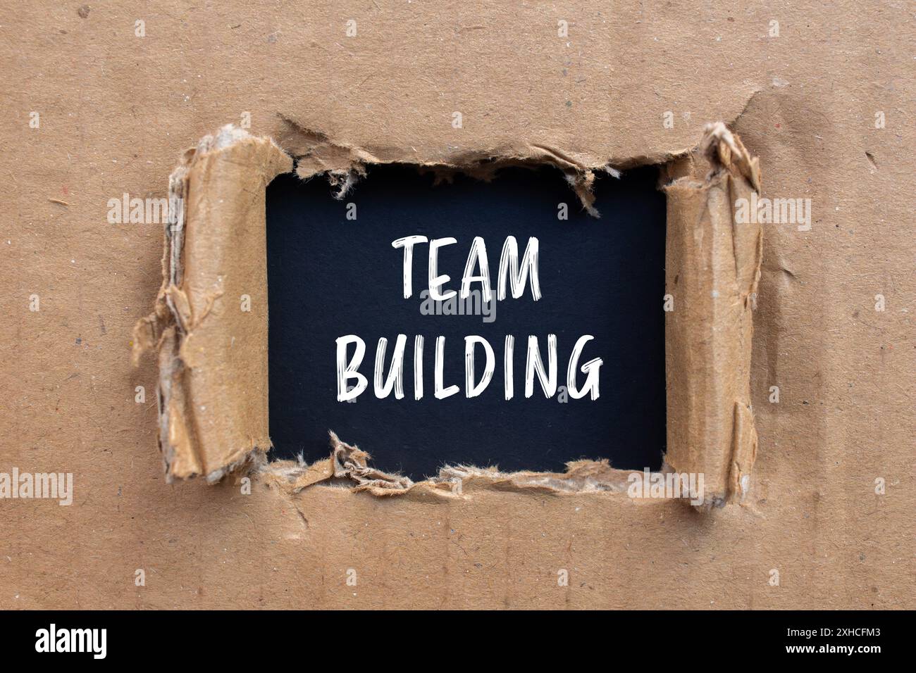 Team building message written on ripped cardboard paper with black ...