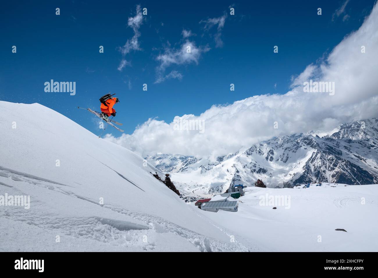 Athlete skier freestyle jumping in orange ski suit in snowy mountains ...