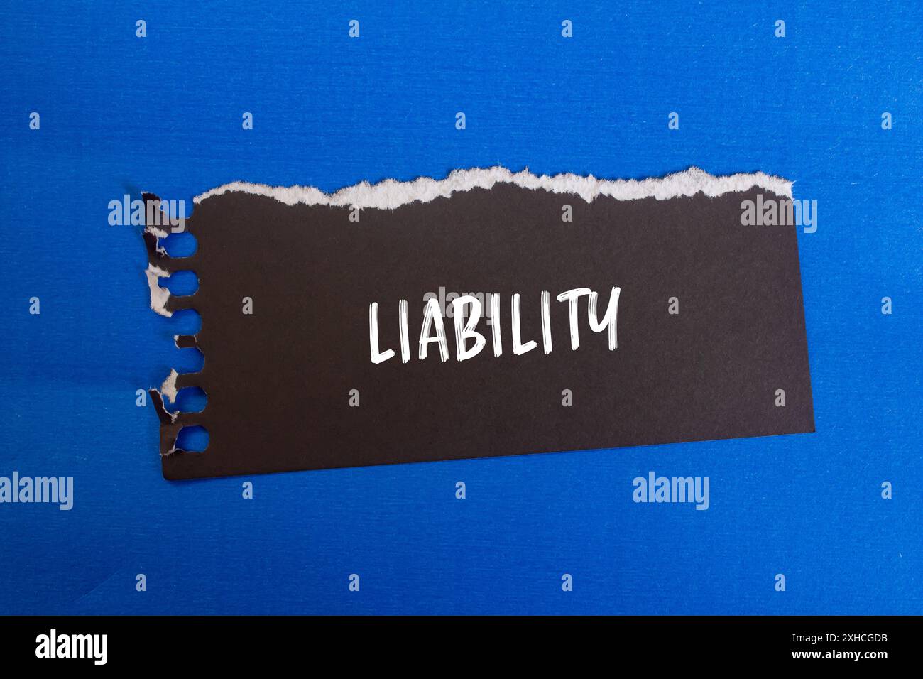 Liability message written on ripped black paper piece with blue ...