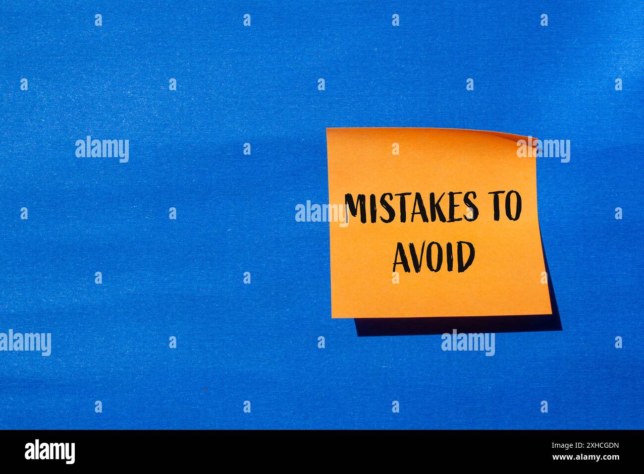 Mistakes to avoid message written on orange paper with blue background ...