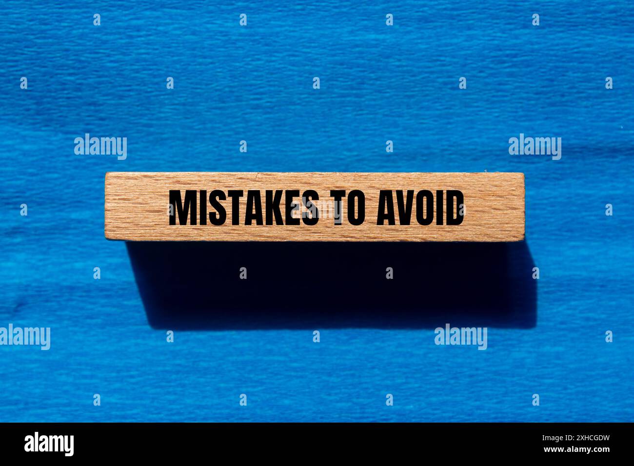 Mistakes to avoid message written on wooden block with blue background ...