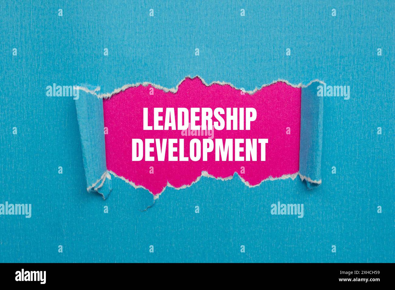 Leadership development message written on ripped blue paper with pink ...