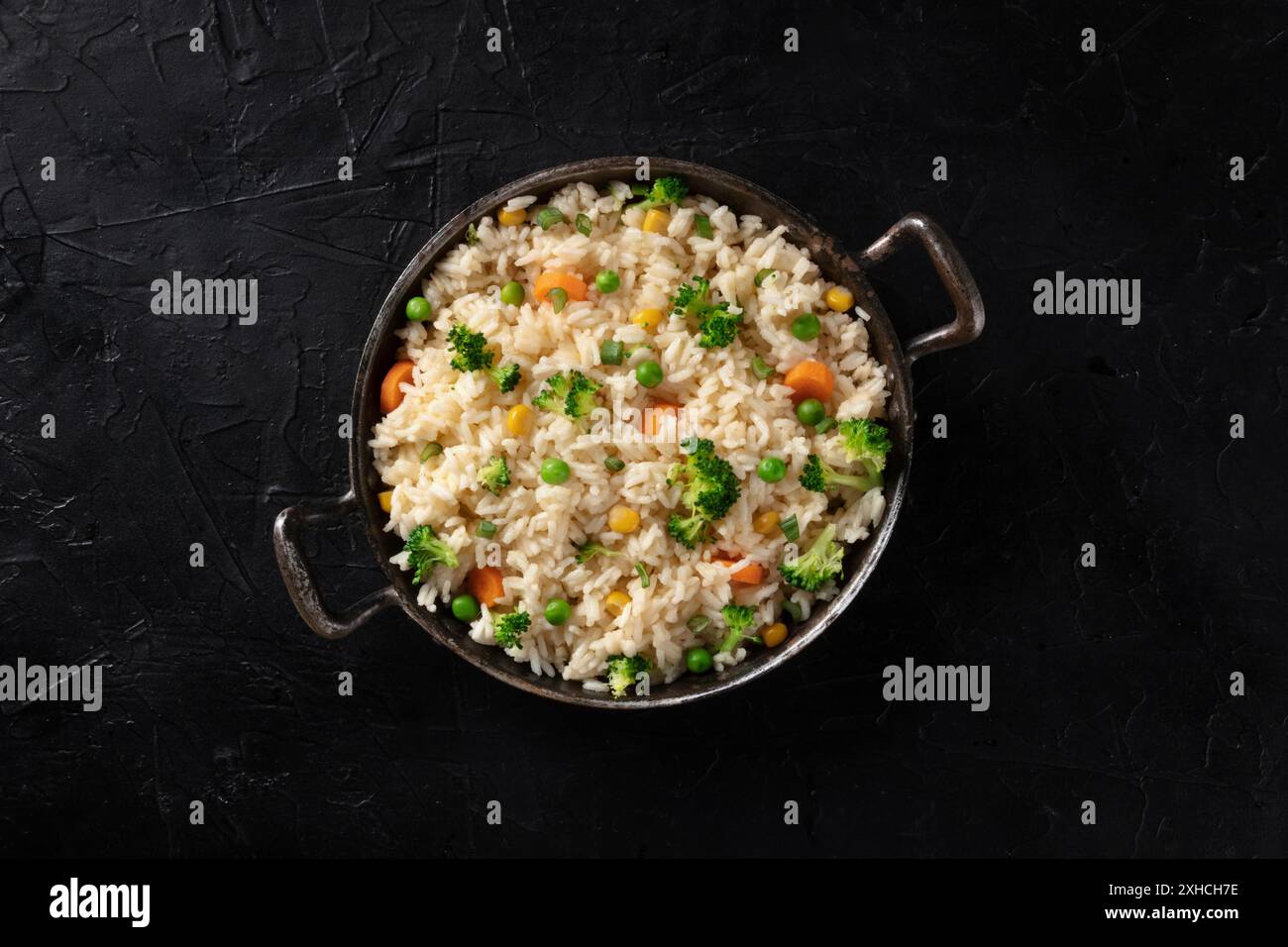 Vegetable rice, shot from the top on a black background. Basmati with ...