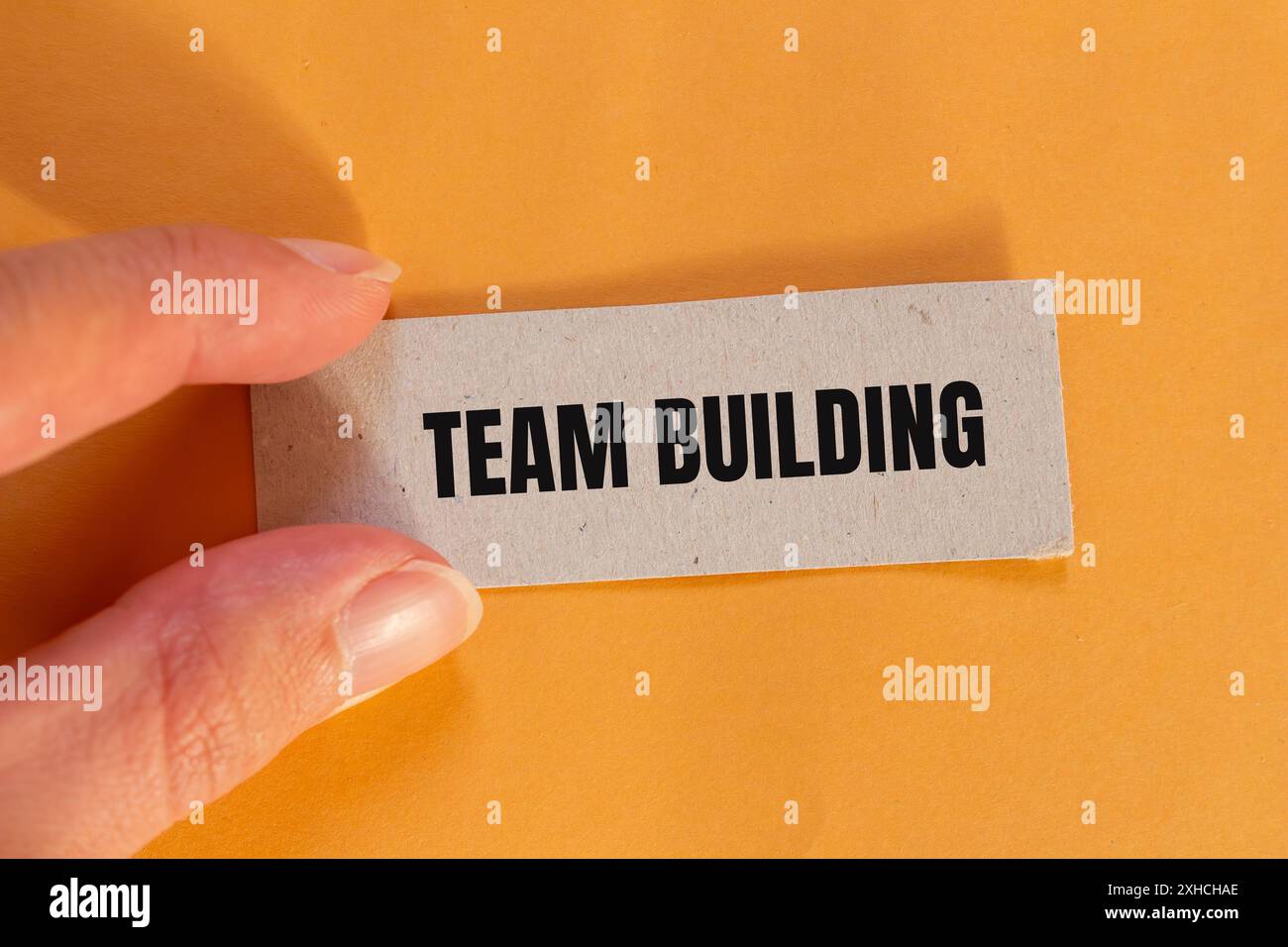 Team building message written on ripped paper piece with orange ...