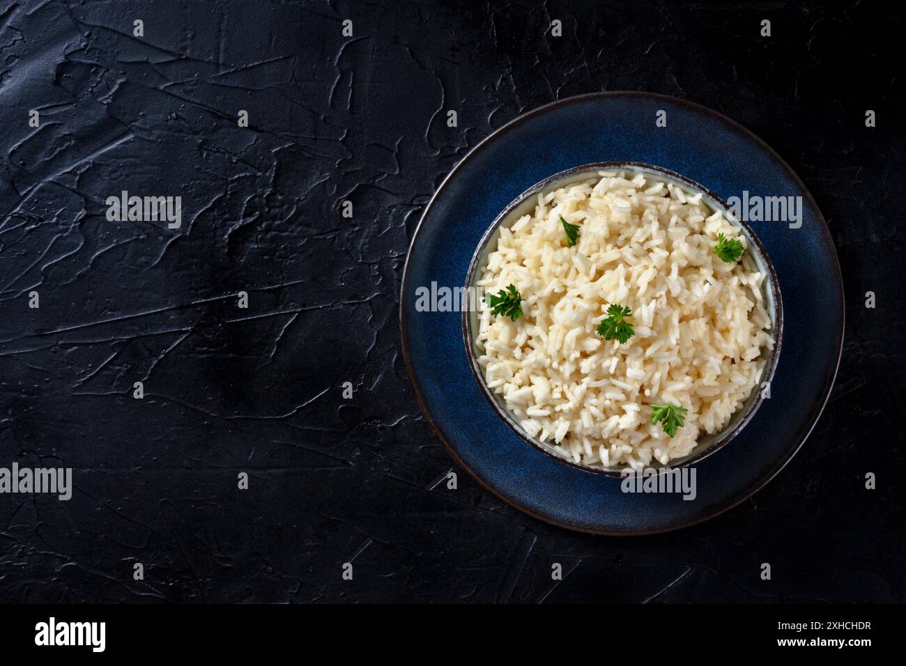 Rice with parsley, top-down shot on a black background. Easy side dish ...