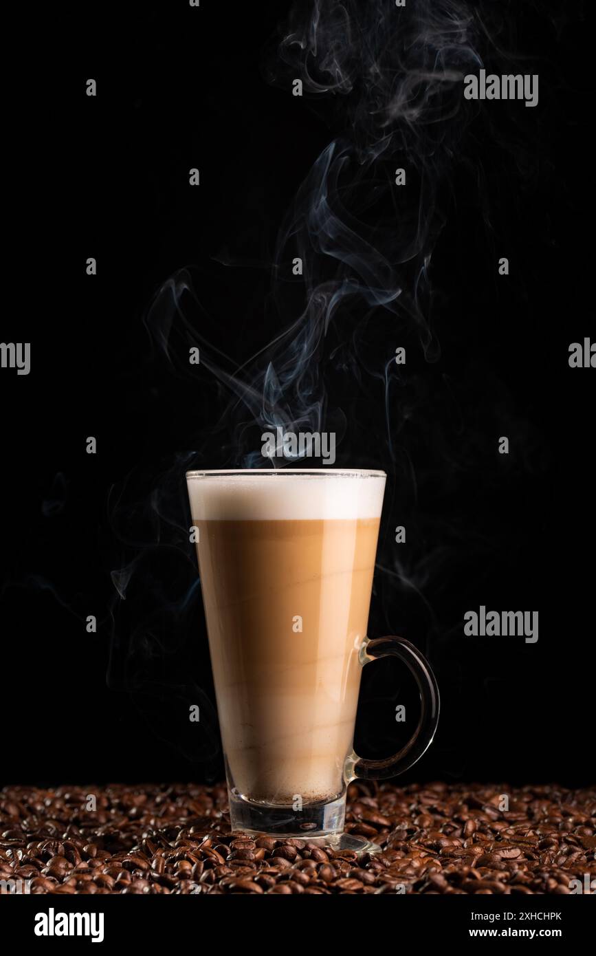 Hot steaming coffee latte with frothy milk in tall glass, on coffee ...
