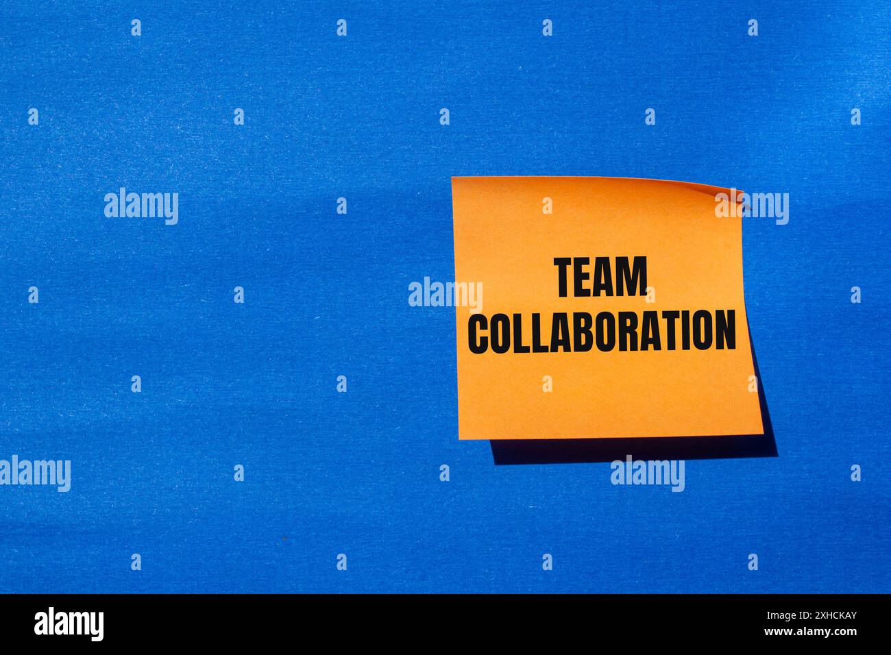 Team collaboration message written on orange paper with blue background ...