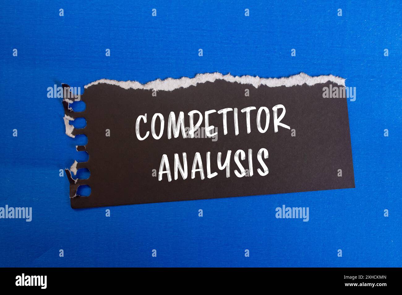 Competitor analysis message written on ripped black paper piece with ...