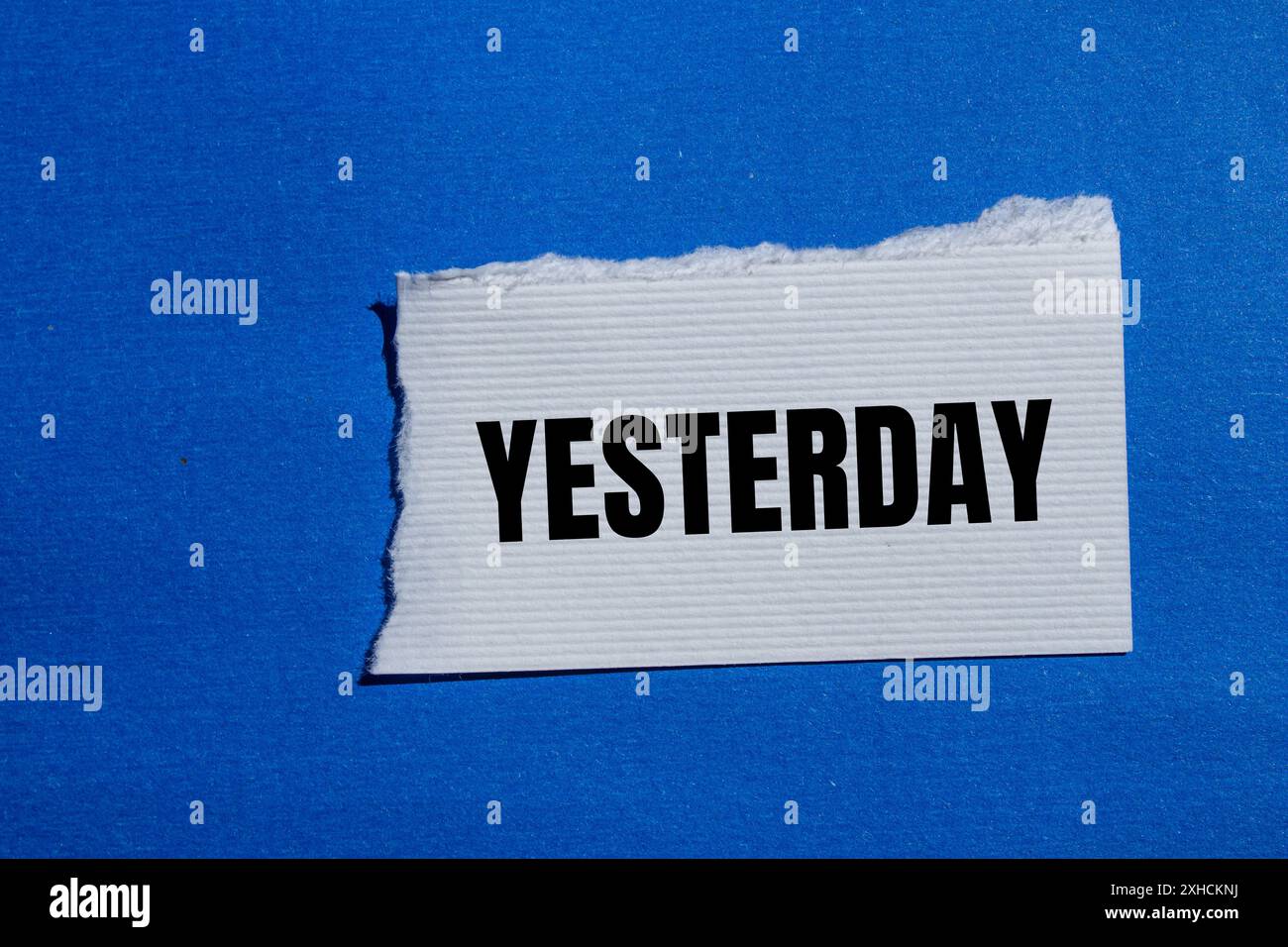 Yesterday word written on ripped white paper piece with blue background ...