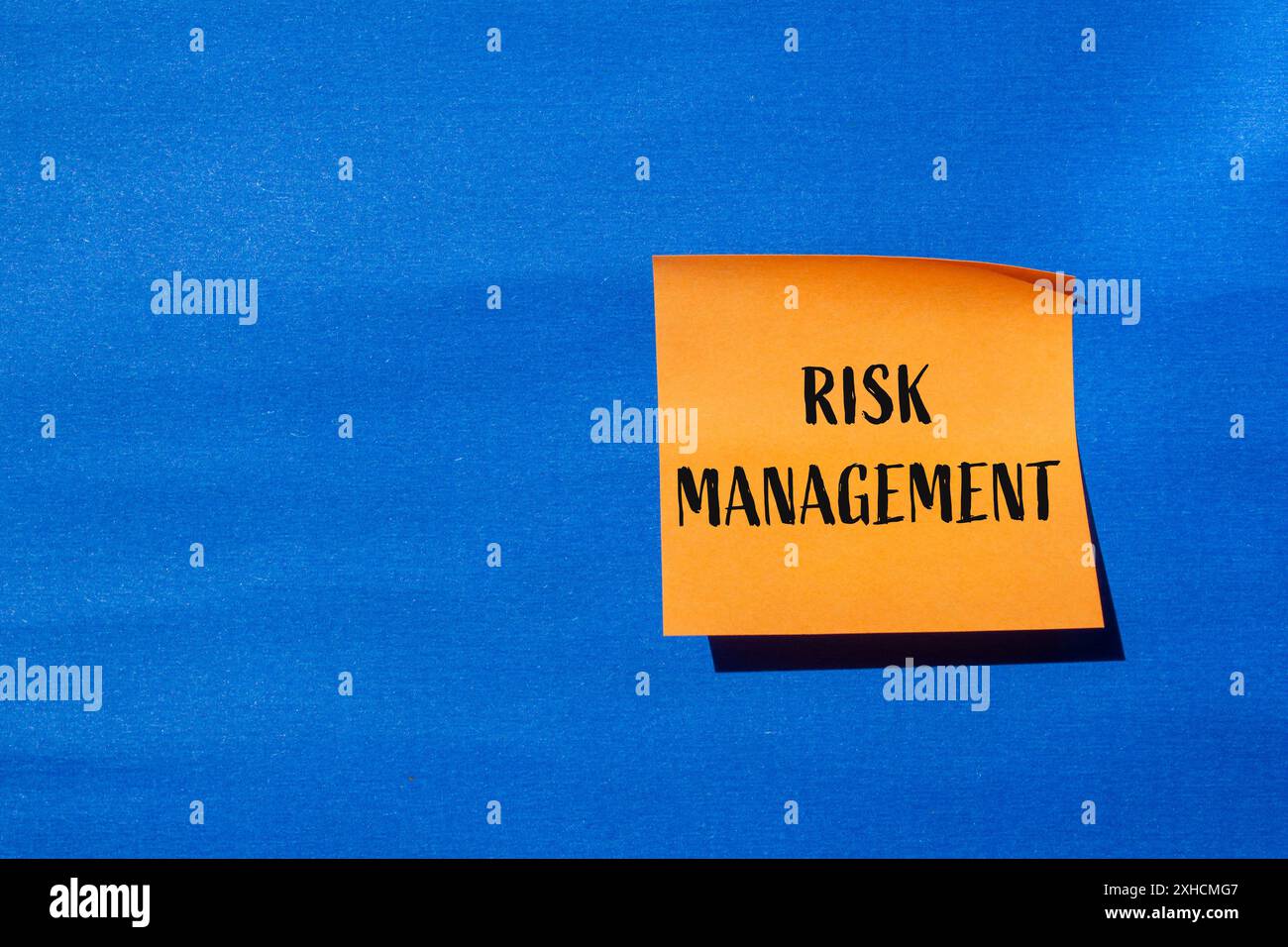 Risk management message written on orange paper with blue background ...