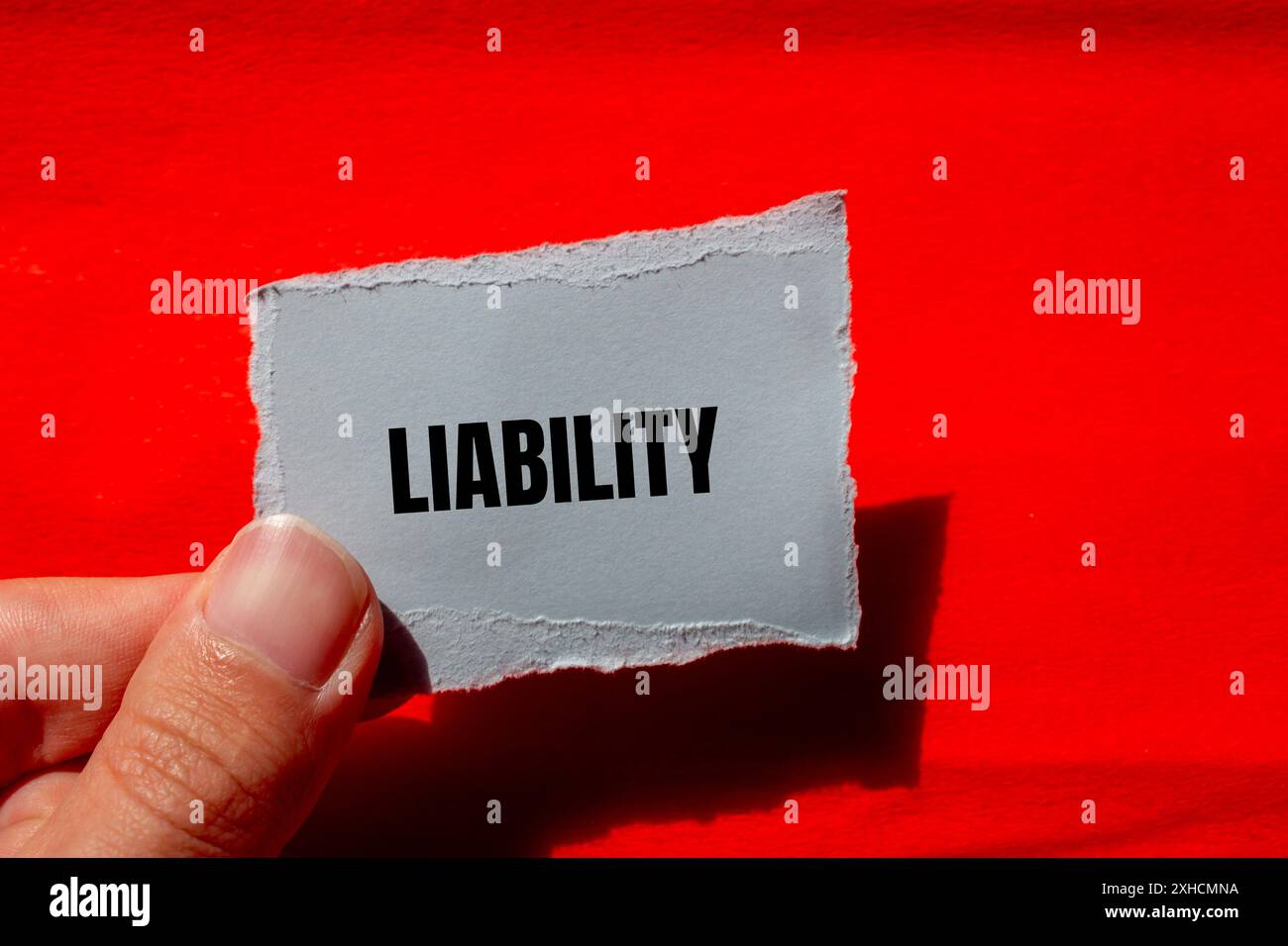 Liability message written on ripped paper piece with red background ...
