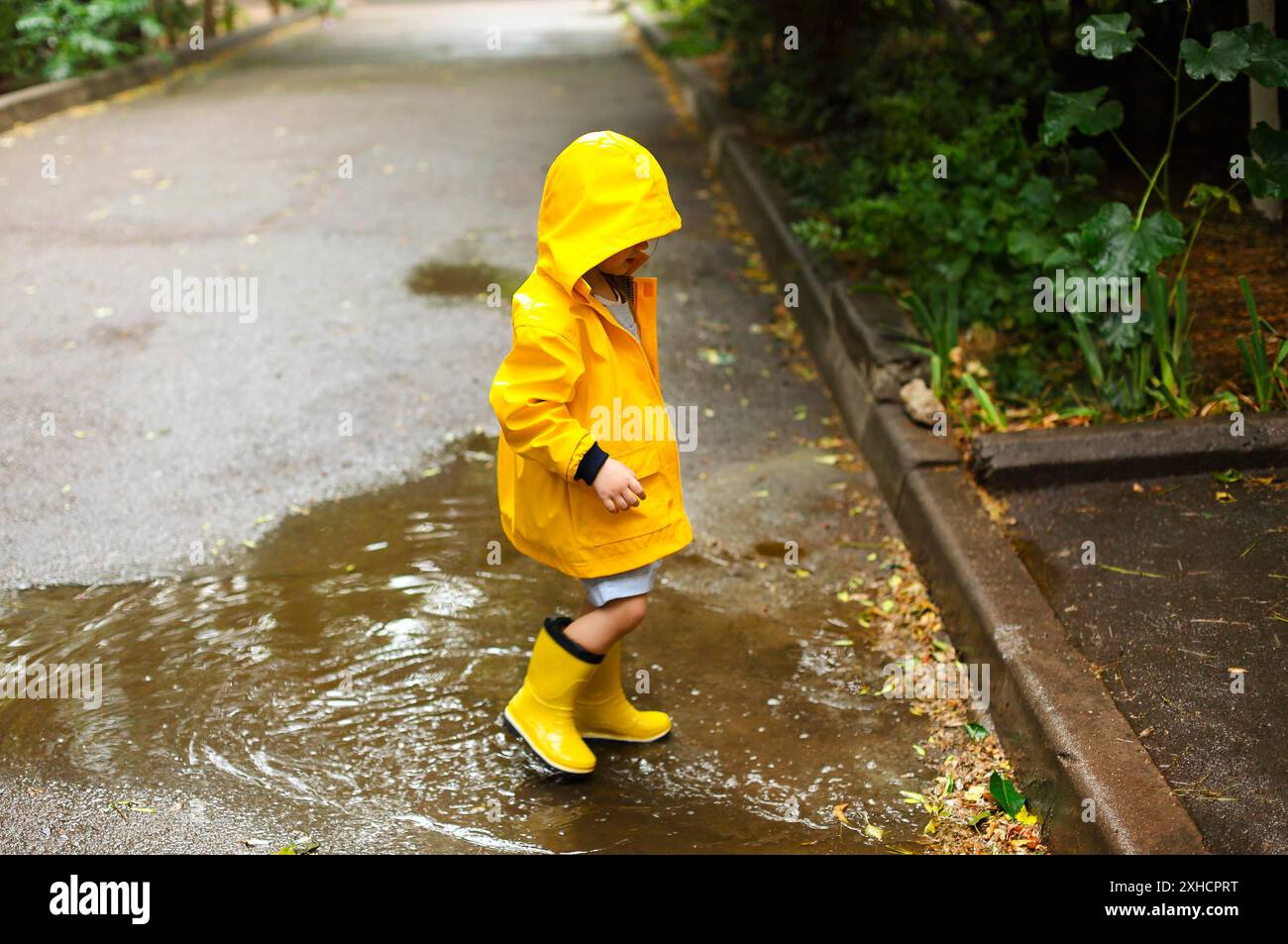 Little girl wearing yellow boots and coat jumping in rainy day Stock ...