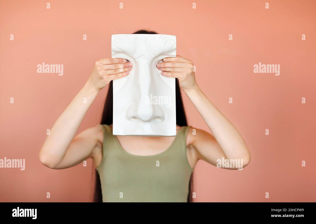 Unrecognizable female covering face with ceramic board in shape of ...