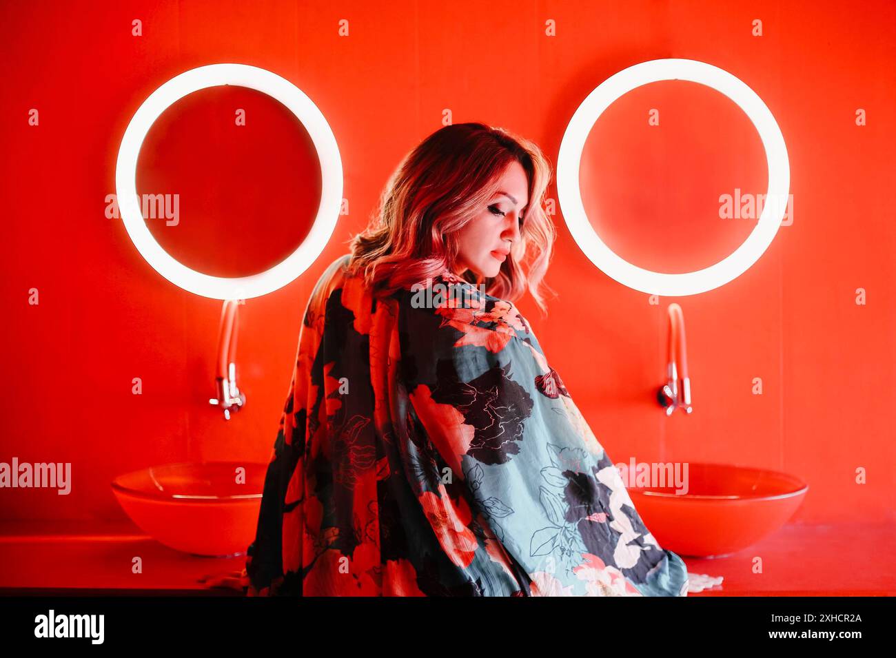 Back view of elegant female standing in contemporary red bathroom with ...