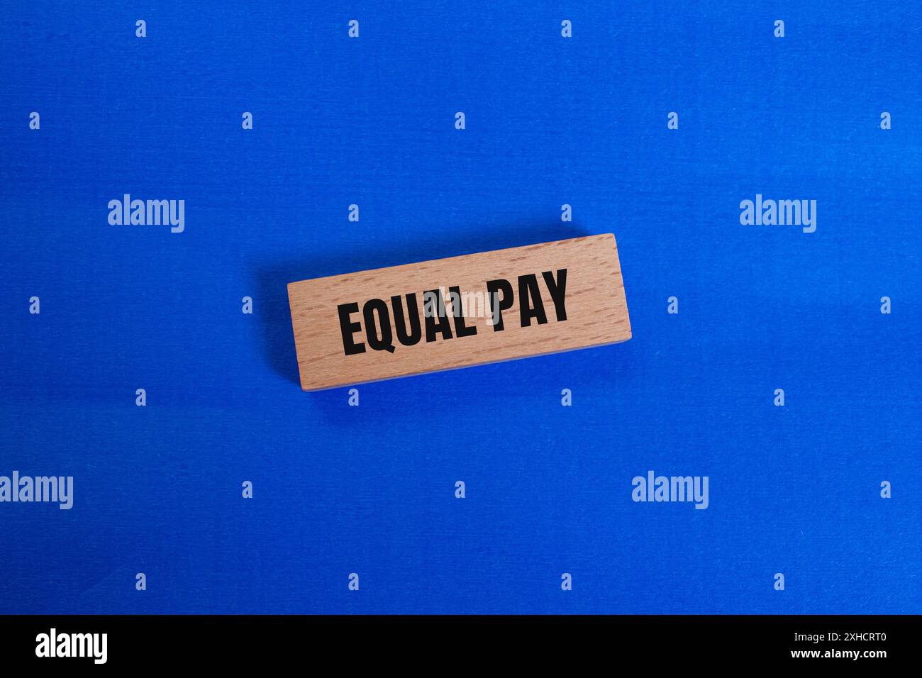 Equal pay message written on wooden block with blue background ...