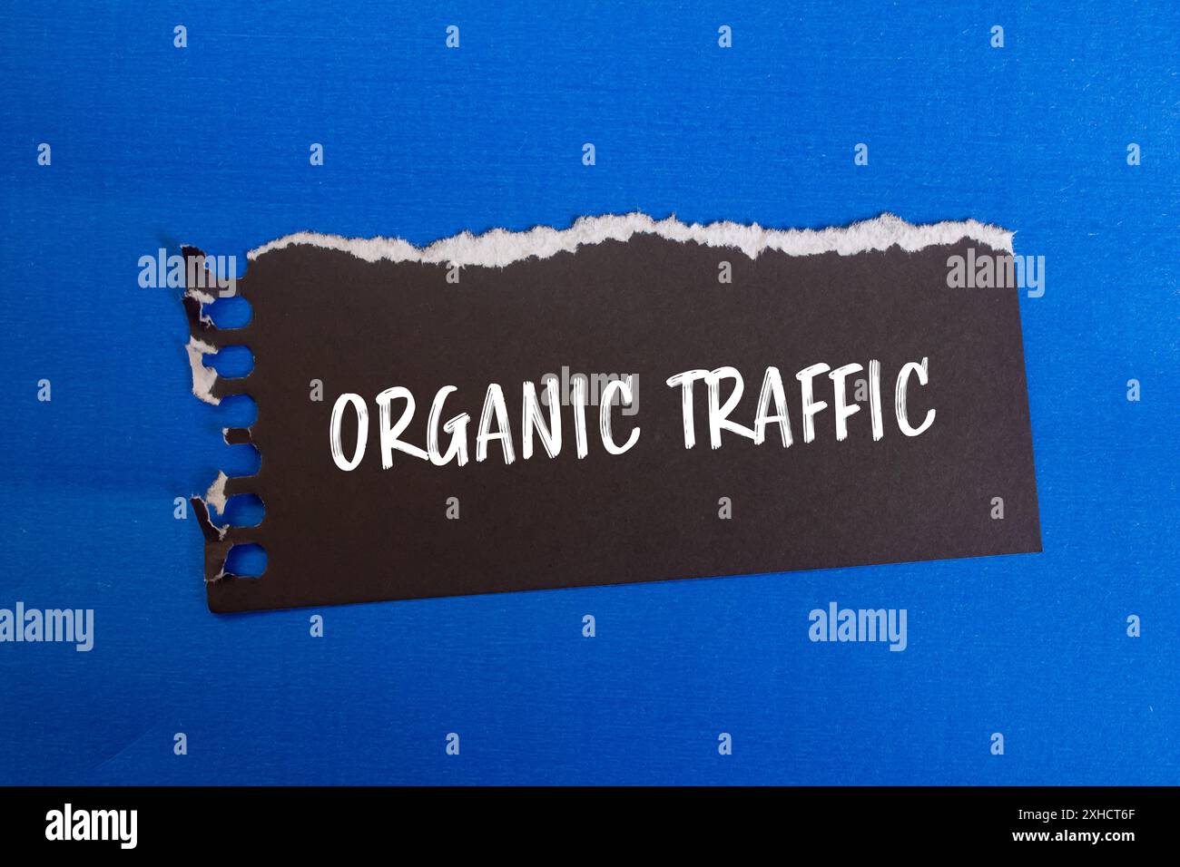 Organic traffic message written on ripped black paper piece with blue ...