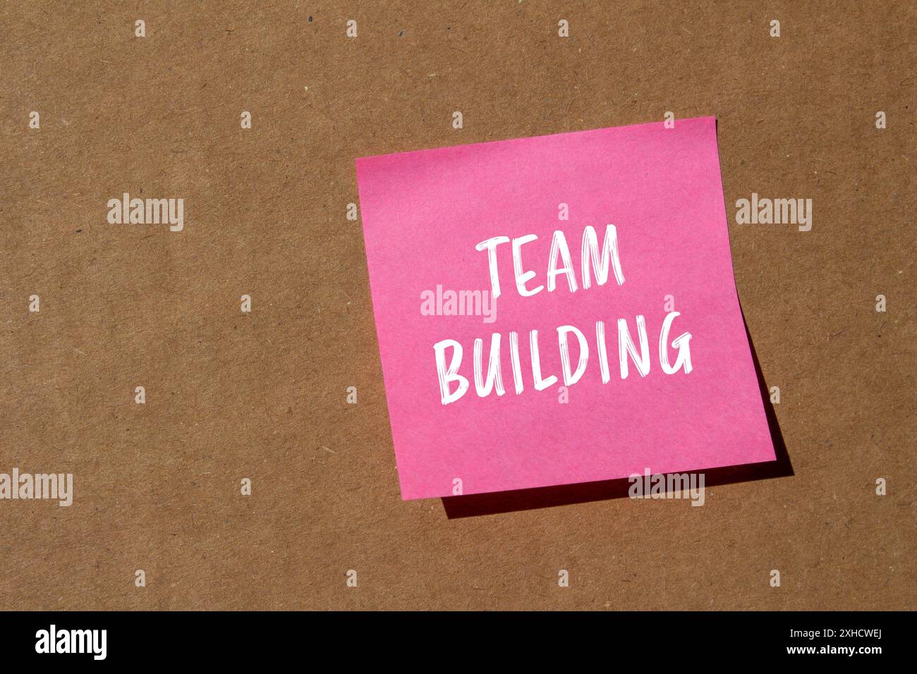 Team building message written on pink paper with cardboard background ...