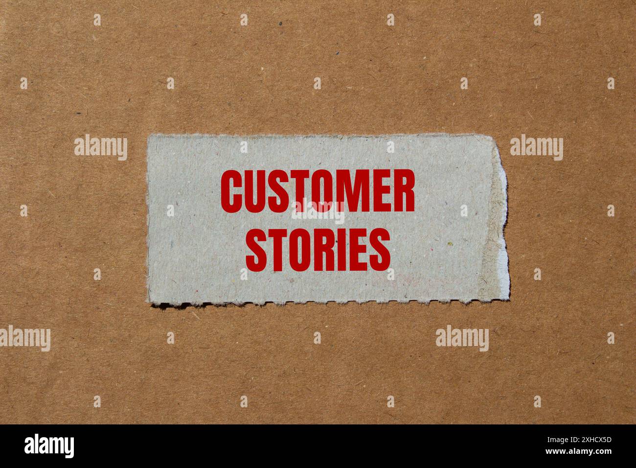 Customer stories message written on ripped paper piece with cardboard ...
