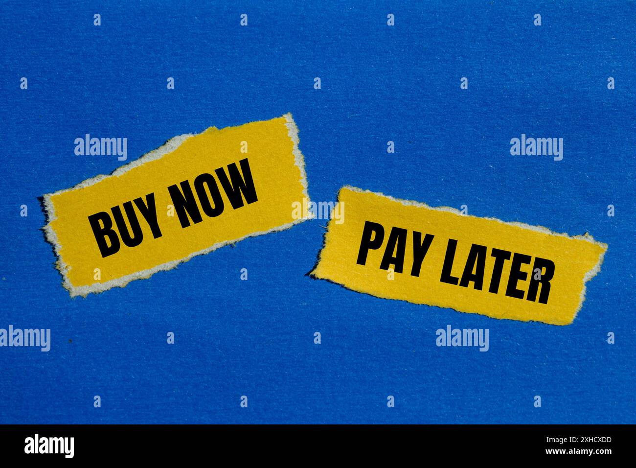 Buy now pay later words written on ripped yellow paper pieces with blue ...