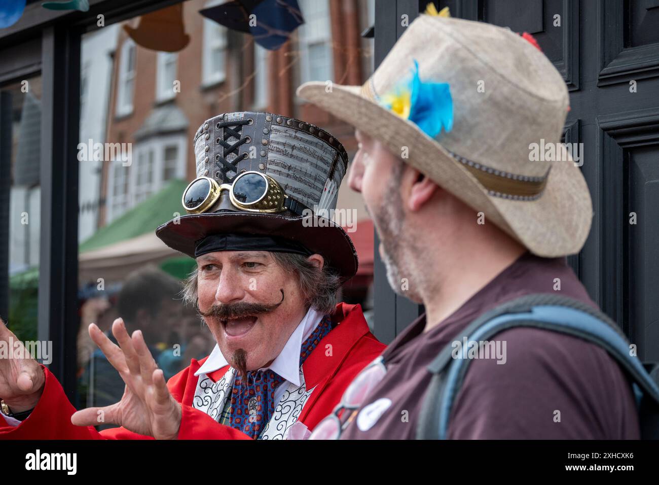 Chesham, UK. 13 July 2024. A street performer wearing a hat entertains ...
