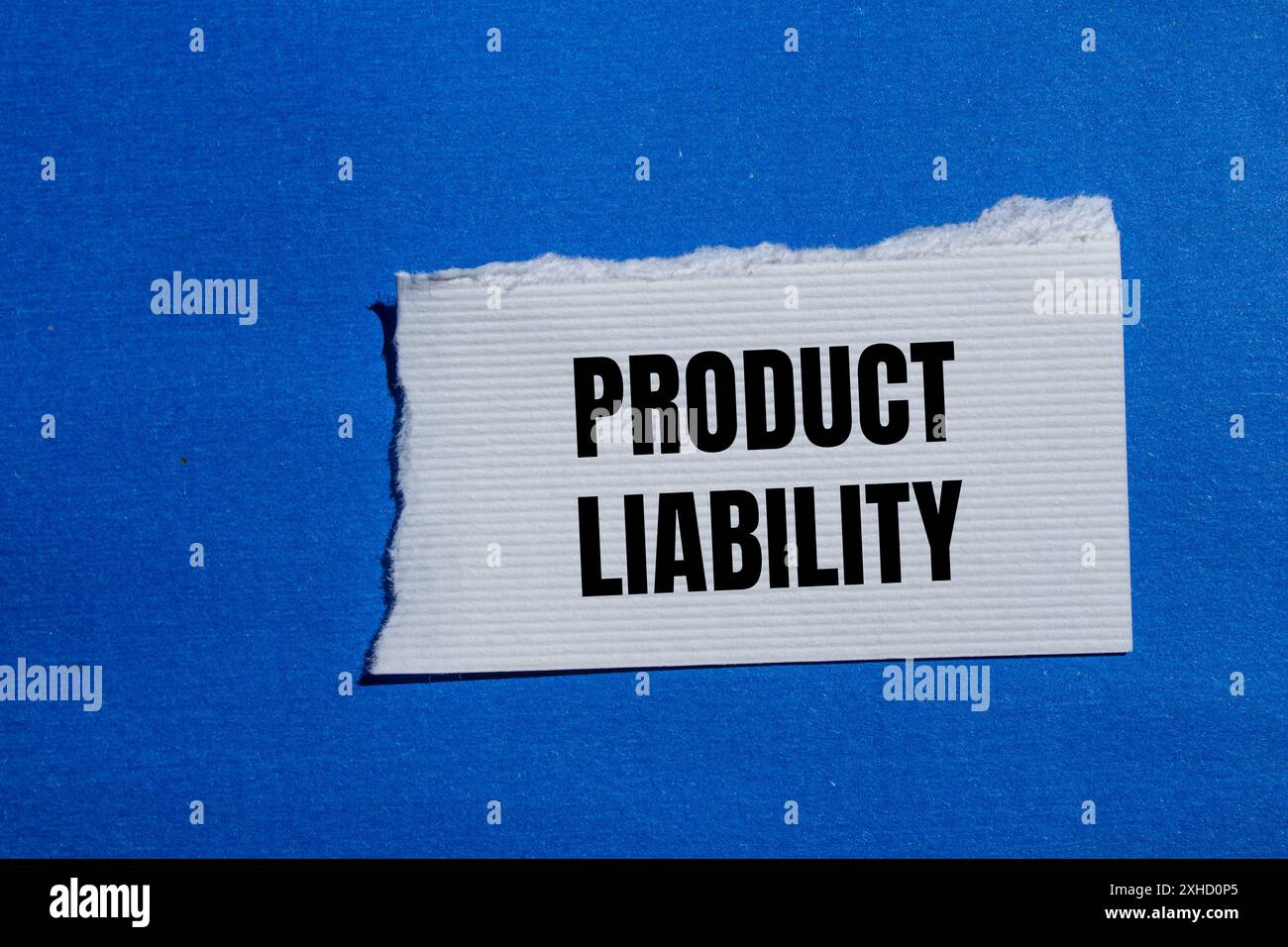 Product liability words written on ripped white paper piece with blue ...