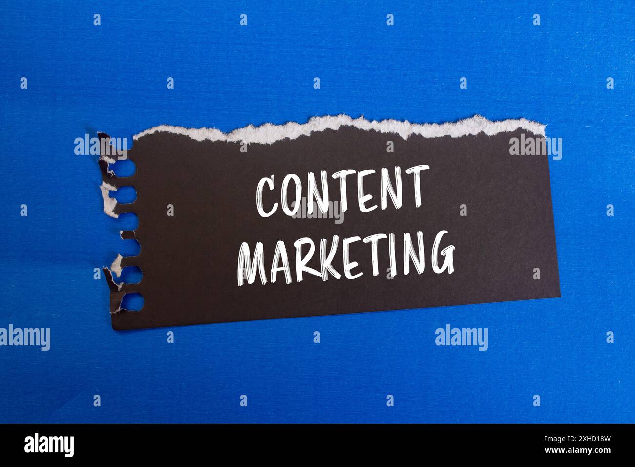 Content marketing message written on ripped black paper piece with blue ...