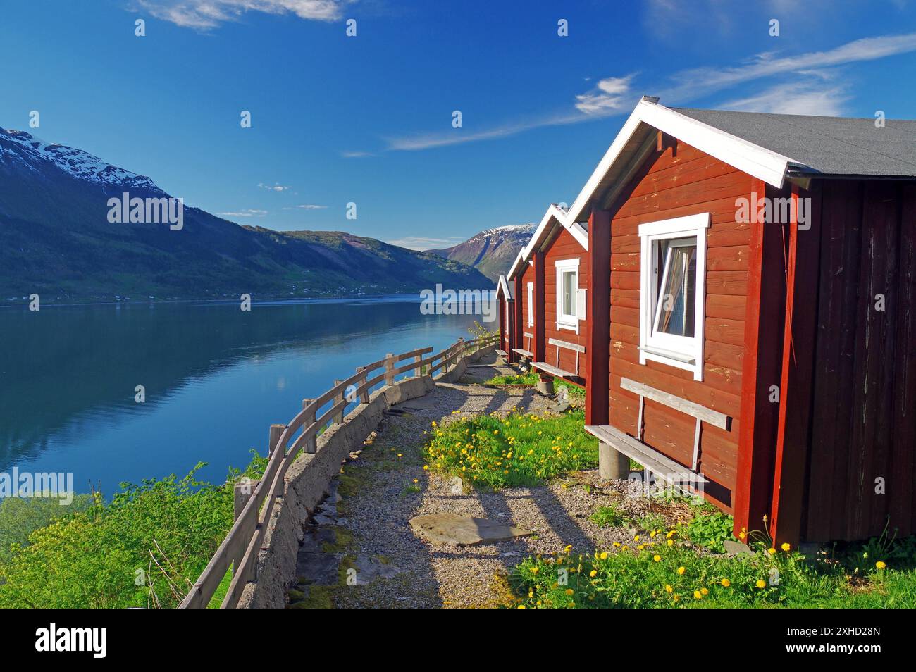 Red wooden cabins on a campsite, view of the fjord and mountains ...