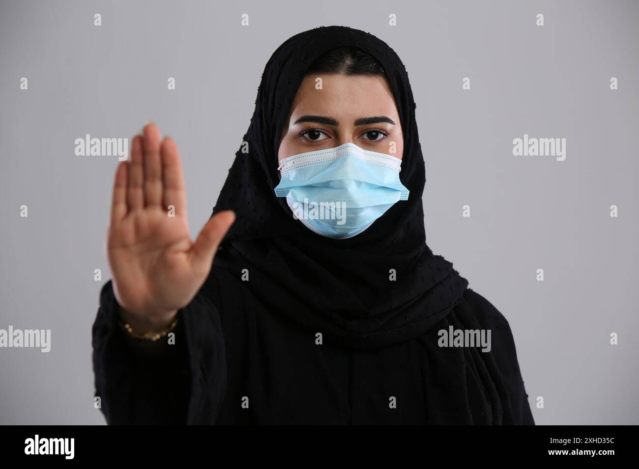 saudi arabian woman in hijaab wearing mask looking at camera with stop sign Stock Photo - Alamy