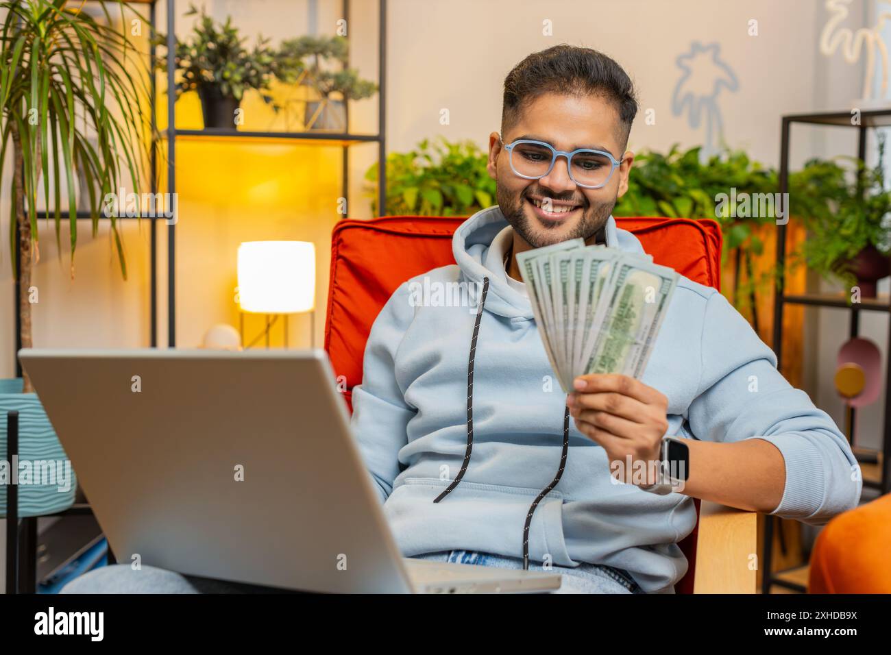 Planning budget. Rich happy Indian man counting money cash use laptop ...