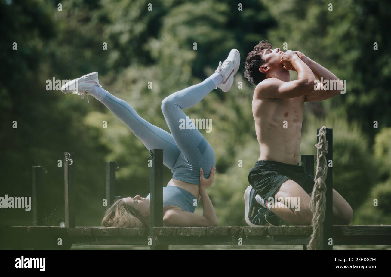 Couple exercising on a wooden bridge in nature performing stretches and ...