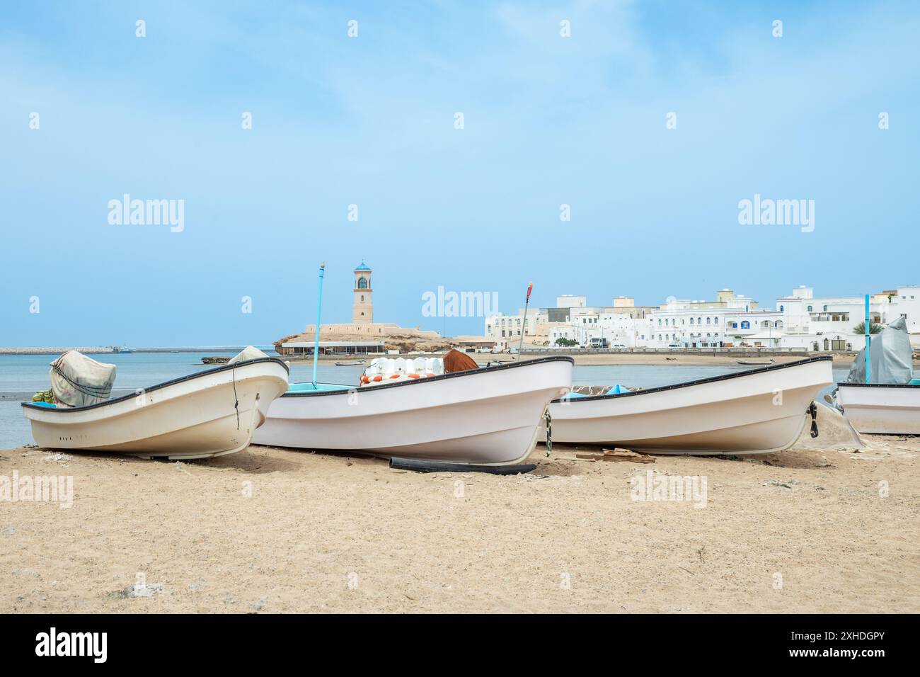 Arab town Sur buildings with lighthouse and fishing boats on a seashore ...