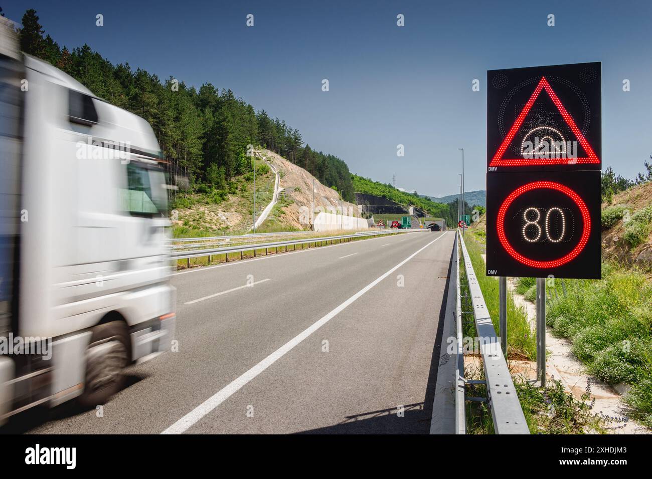 A white truck drives past a speed limit sign on a highway. The sign ...