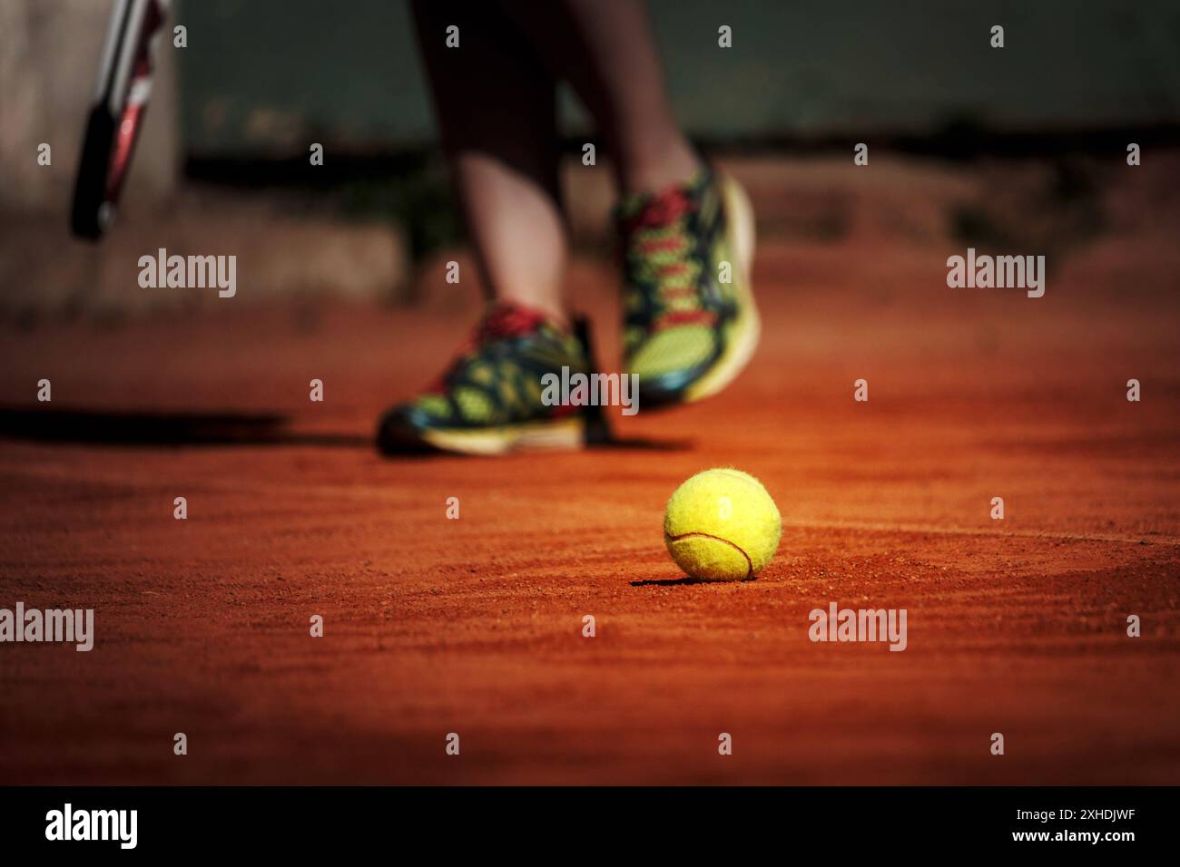 A tennis player prepares to serve a ball on a clay court Stock Photo ...