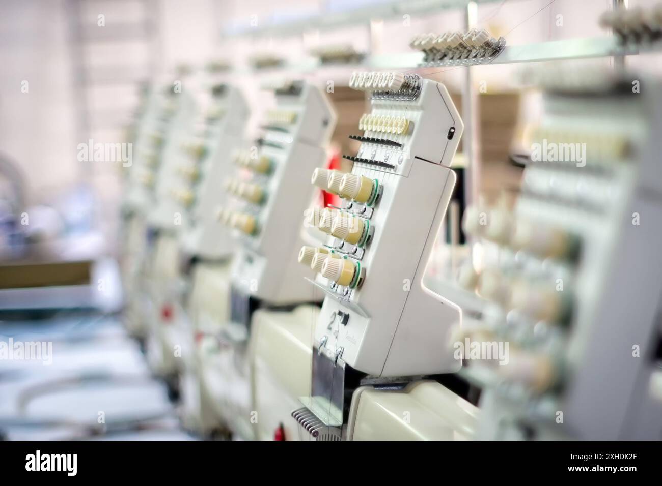 Several industrial embroidery machines are lined up in a factory ...