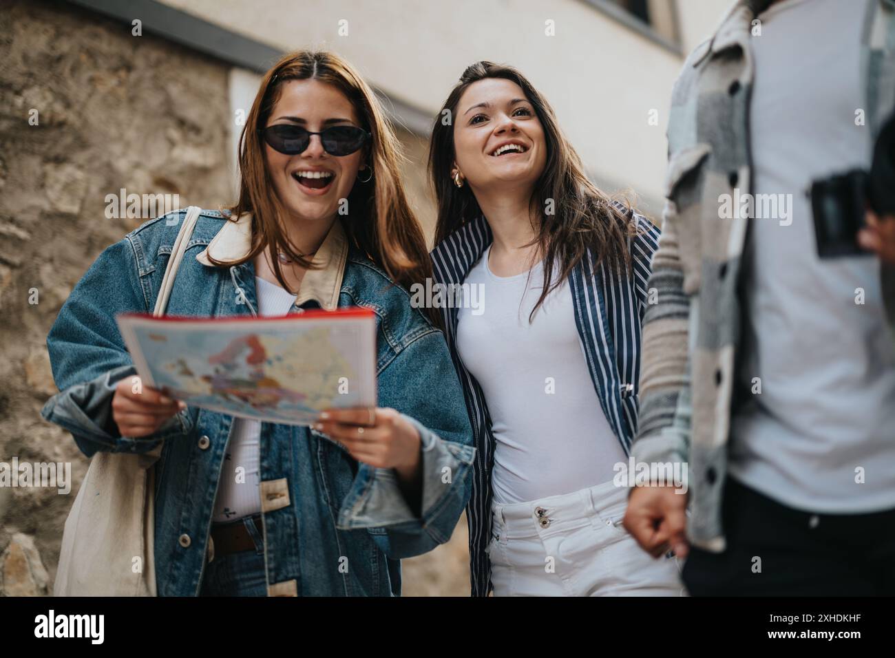Young friends exploring a sunny city, laughing while holding a map ...