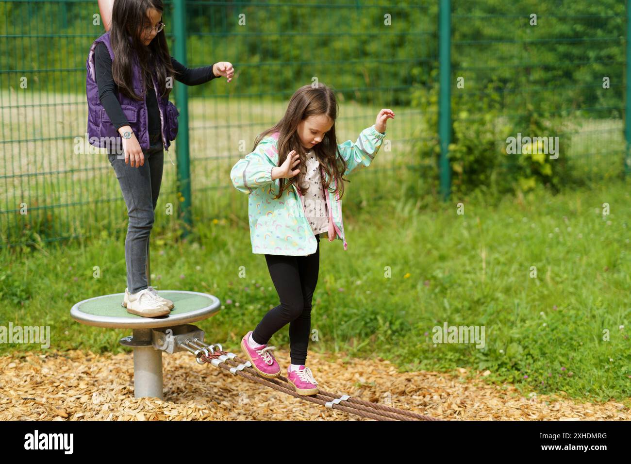 Two little girls are playing on the playground. Children balancing on a ...