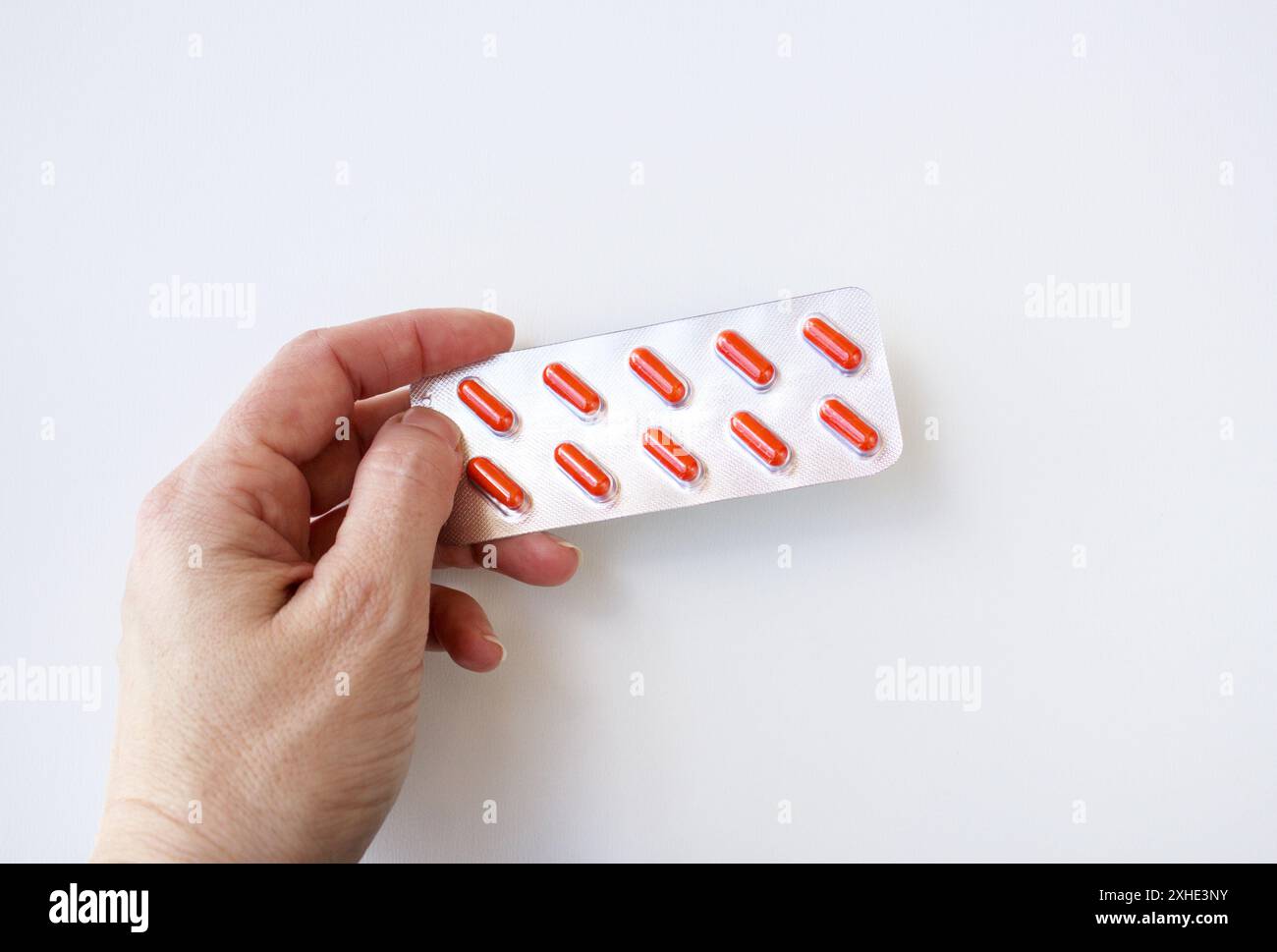 Human hand holding red medical capsules packed in blister. Caucasian ...