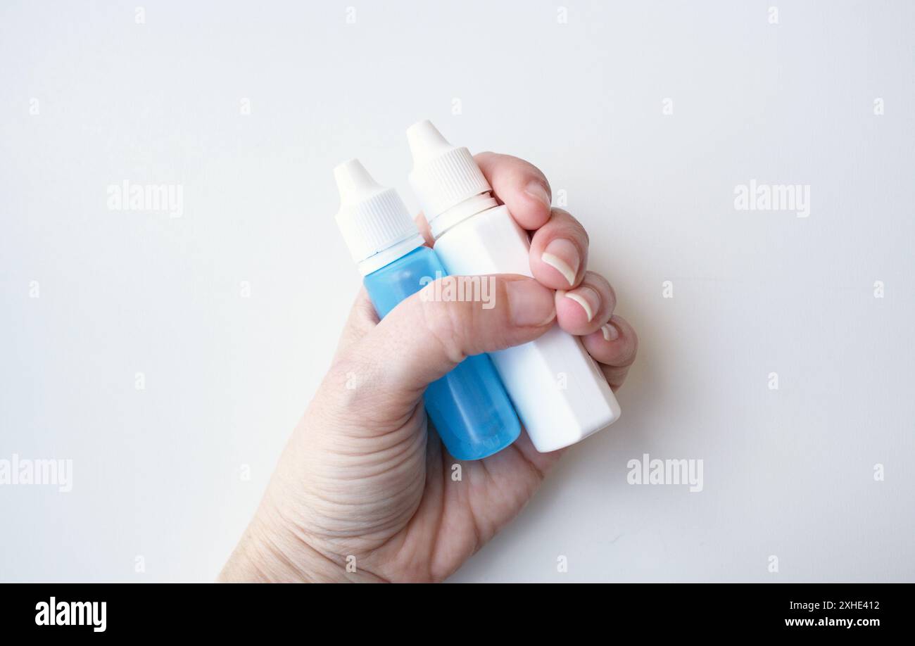 White human hand holding medical squeezable droppers for glaucoma ...