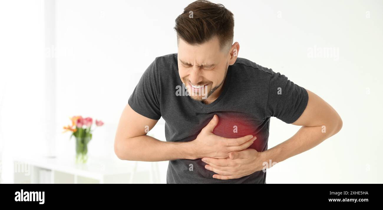 Heart attack. Man writhing in pain and pressing hands to chest on grey ...