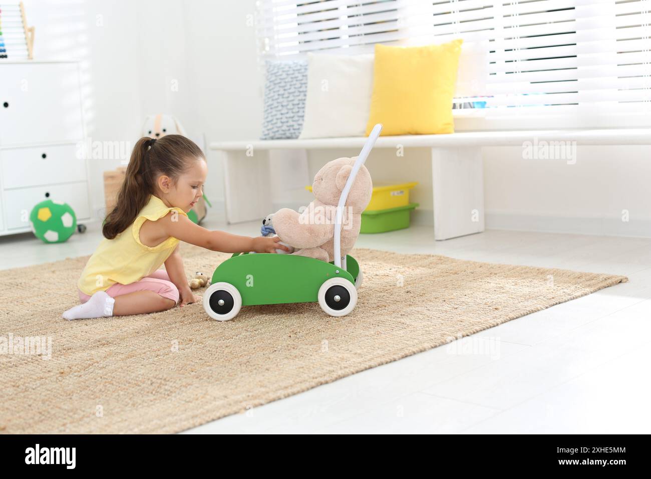 Cute little girl playing with toy walker and teddy bear at home Stock ...
