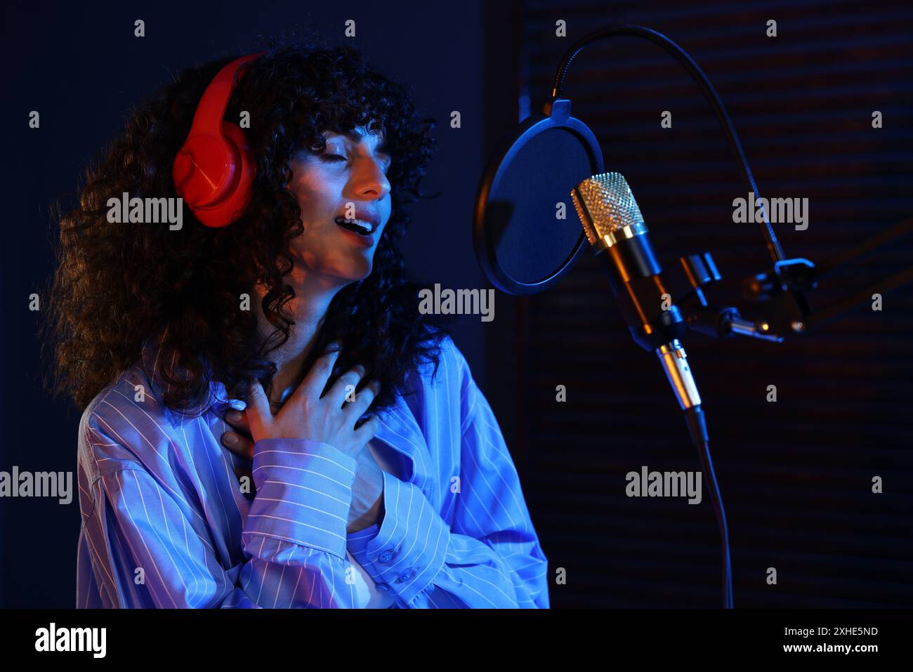 Vocalist singing into microphone in professional record studio with ...