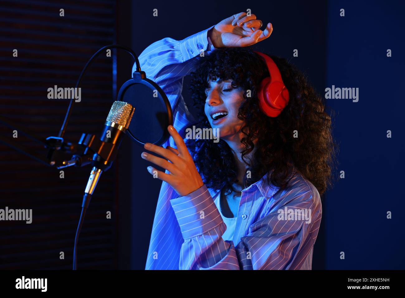 Vocalist singing into microphone in professional record studio with ...