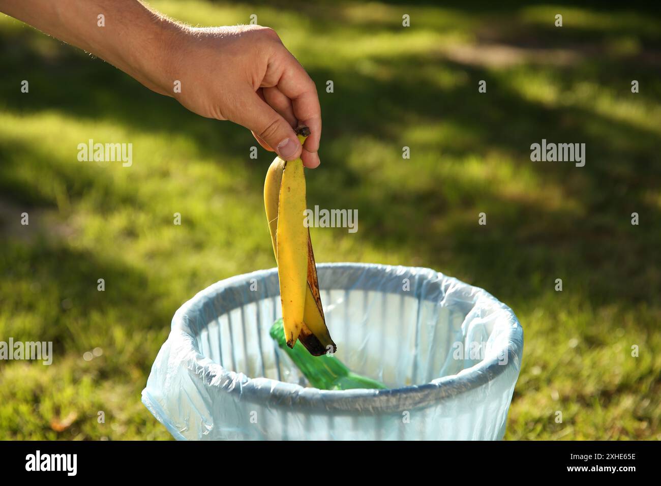 Man throwing banana peel into garbage bin outdoors, closeup Stock Photo ...