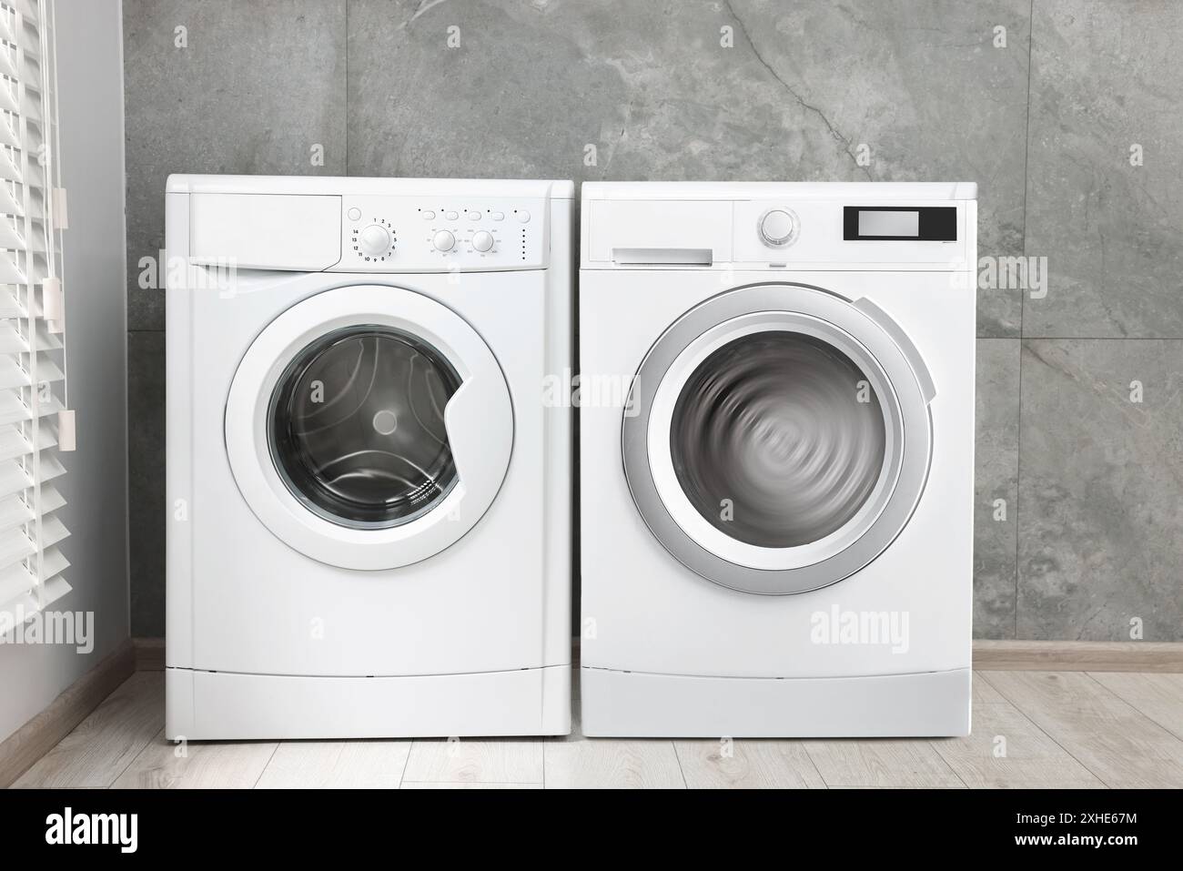 Two washing machines near tiled wall in laundry room Stock Photo - Alamy